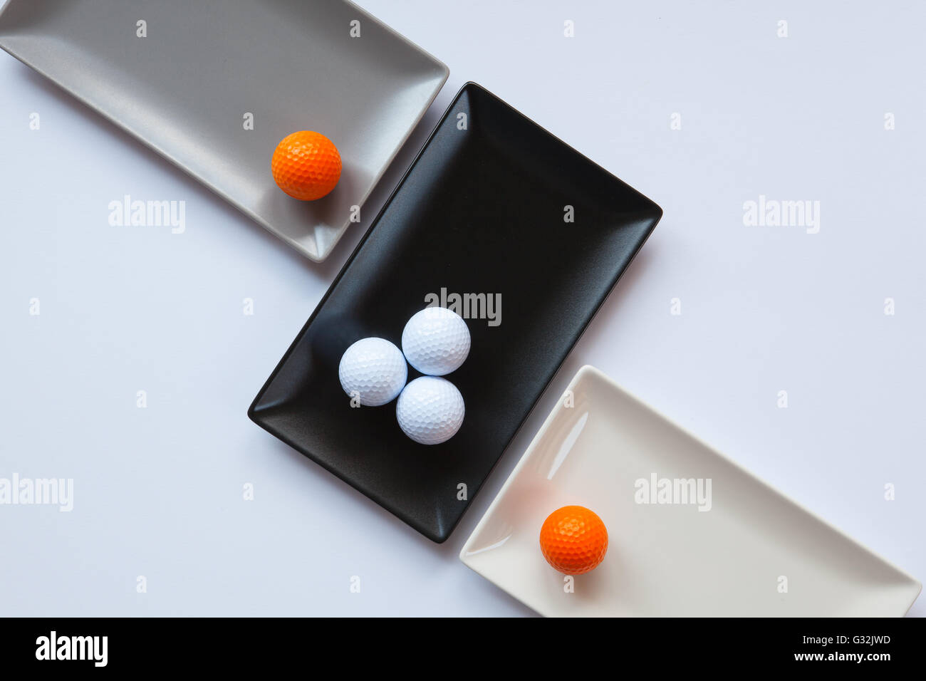 Different ceramic dishes with golf balls on over white background ...