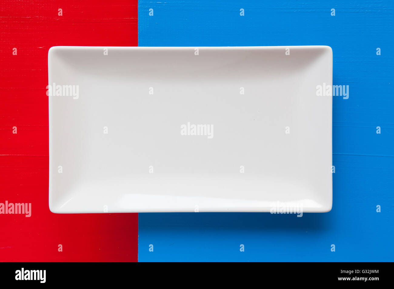 Empty white ceramic dish on over blue and red background, rectangle ...