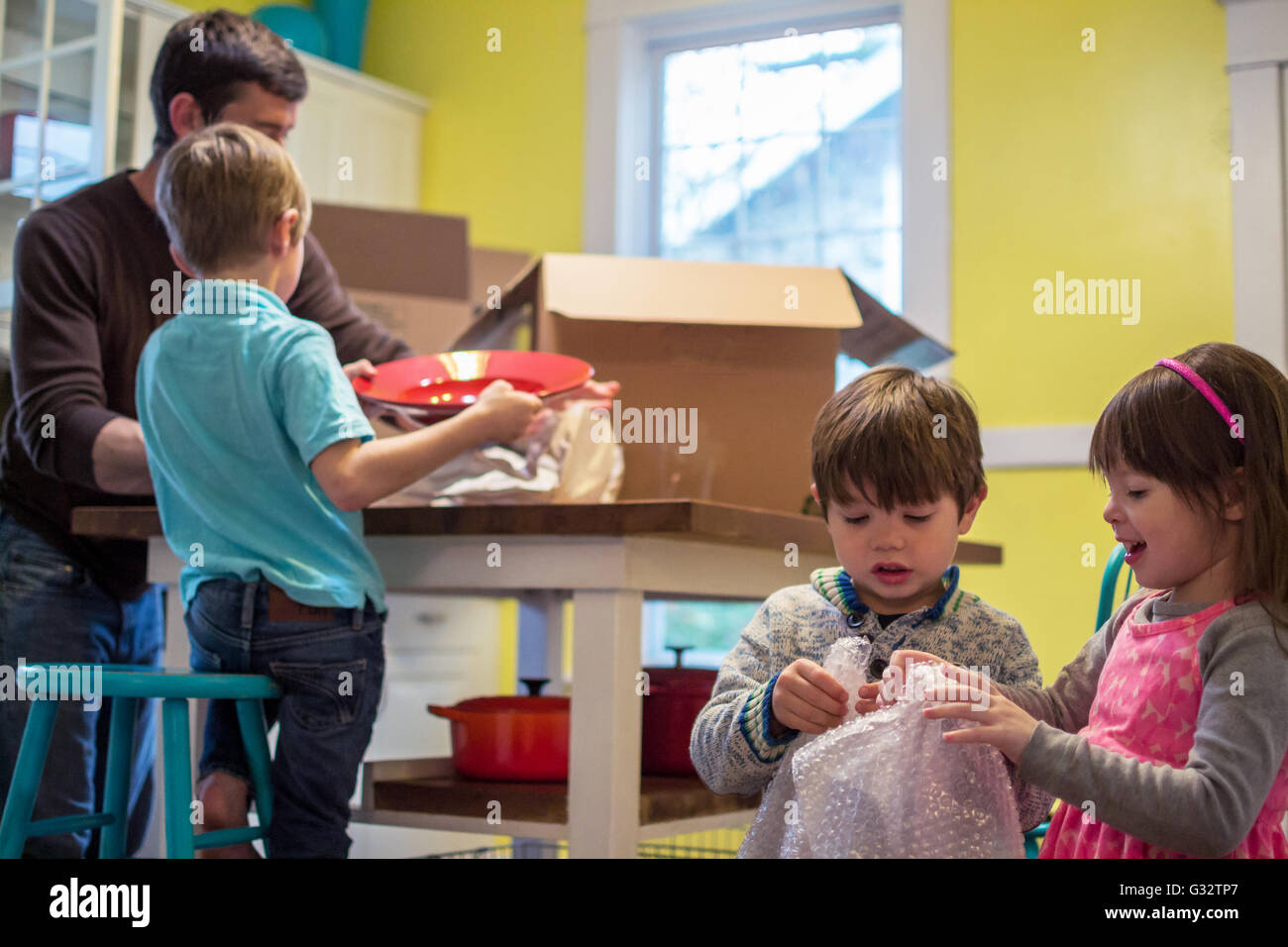 Father and son packing while brother and sister play with bubble wrap ...