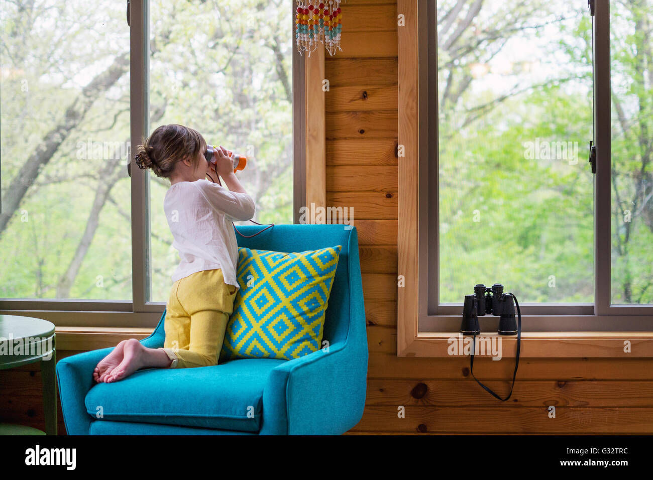 Girl looking out of window with binoculars Stock Photo - Alamy