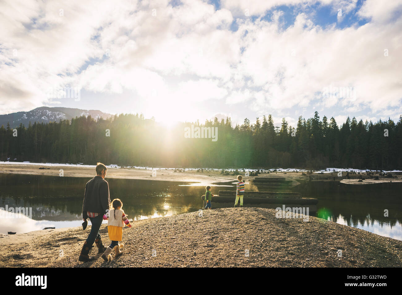 Father walking by lake with three children Stock Photo - Alamy