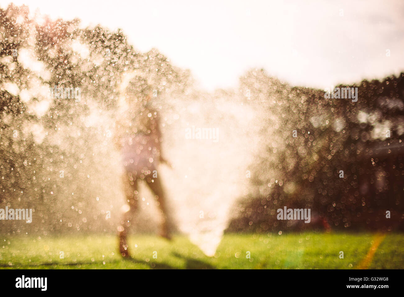 Girl running through sprinkler hi-res stock photography and images - Alamy