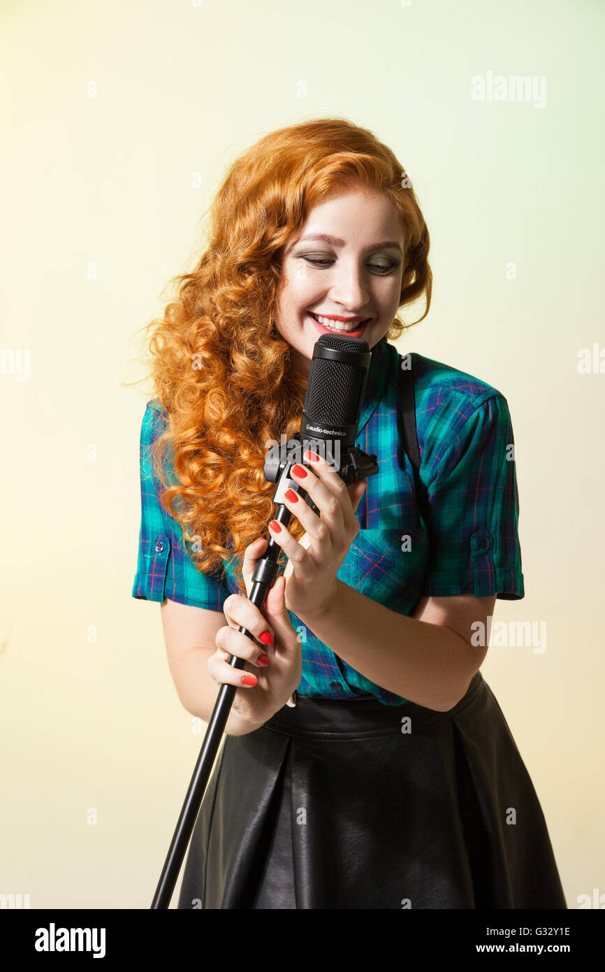 Curly-haired beautiful singer smiling while performing song in mic ...
