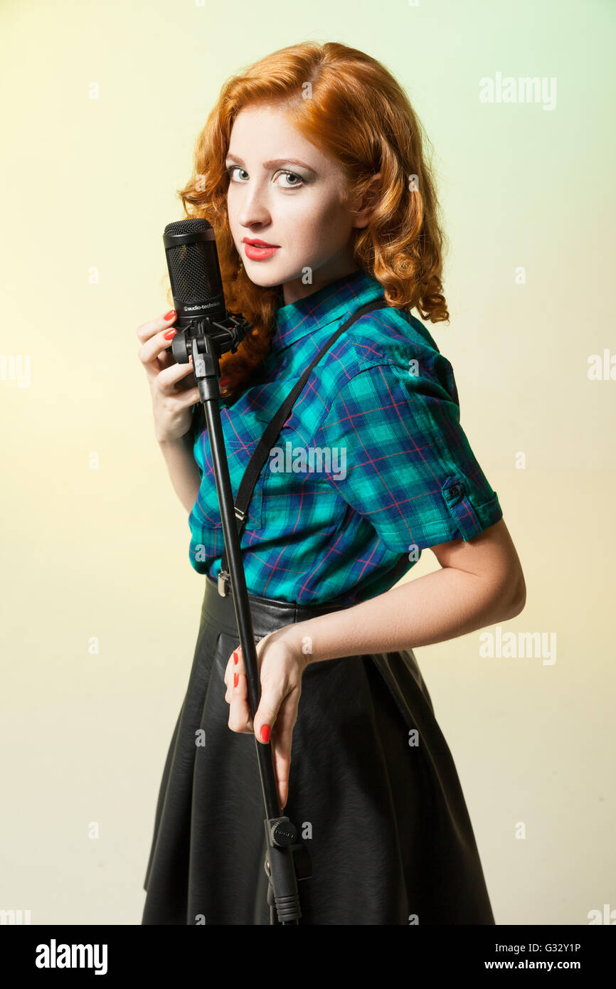 Portrait of attractive singer with red hair singing in mic.Studio shot ...