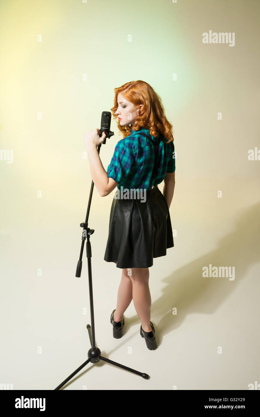 Back view of red-haired singer with mic.Studio shot Stock Photo - Alamy