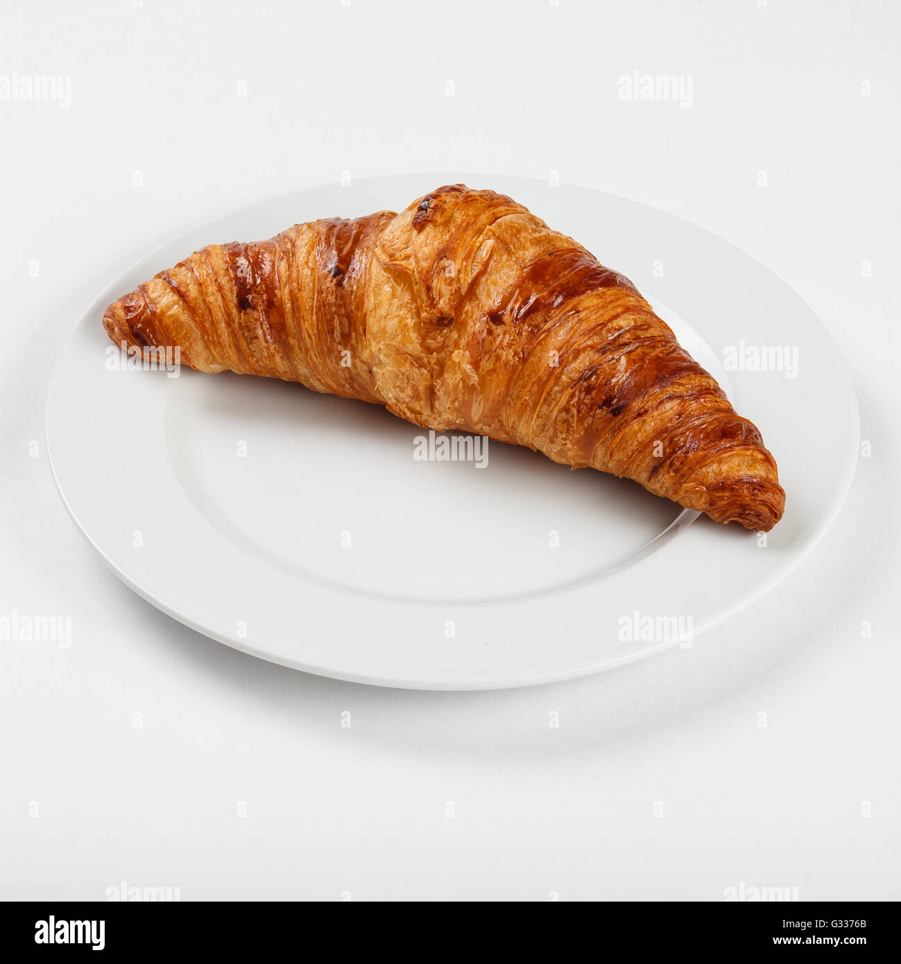 Delicious croissant on the plate on white background. Close up side ...