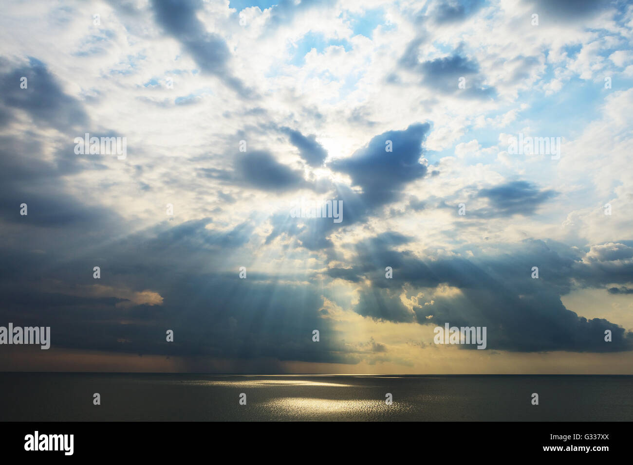 Cloudy seascape after storm seeing natural sunbeams at sunset. Sun rays ...