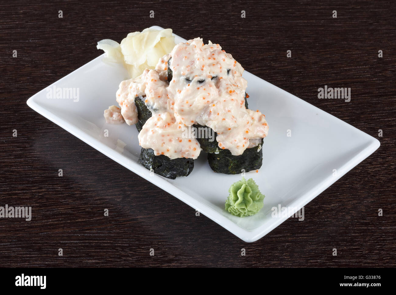Sushi rolls on a plate with flying fish roe on dark brown wooden table ...
