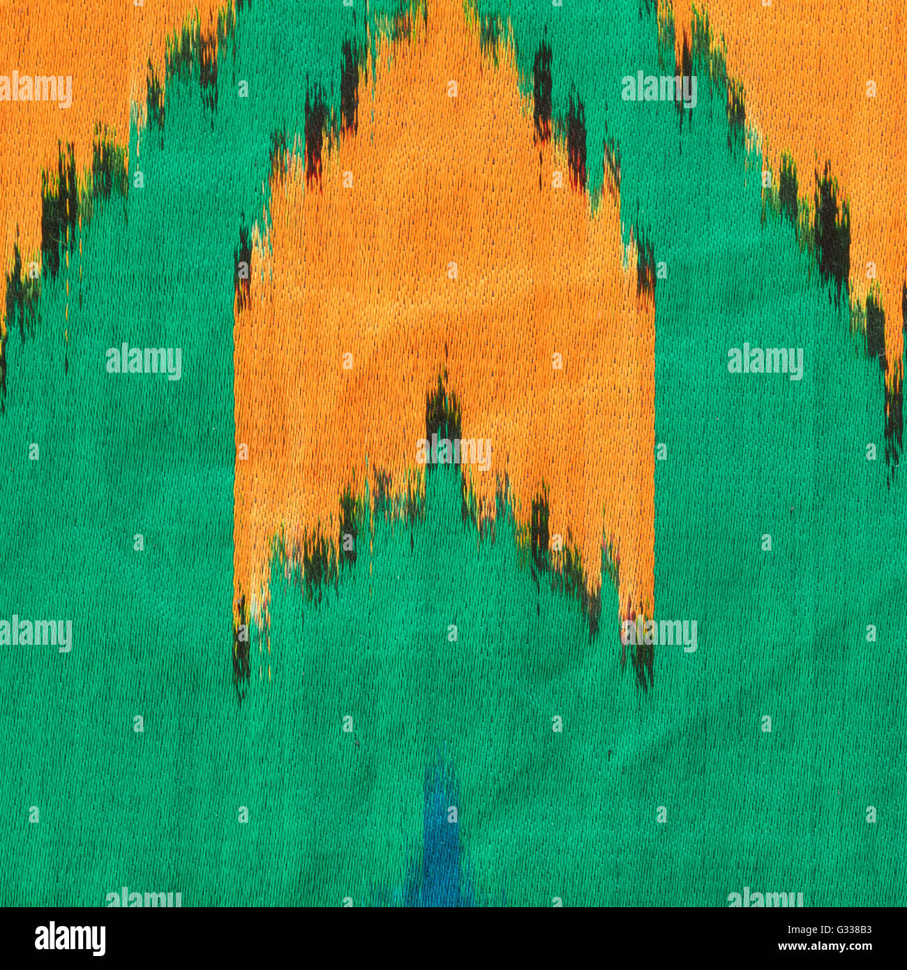 Uzbek silk atlas Ikat. Orange, green and blue ornament. Close up ...