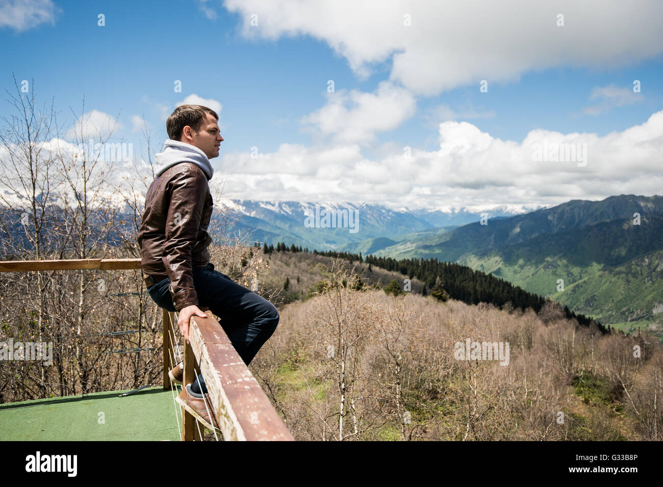 Young man looking at the view from a top of mountain Stock Photo - Alamy
