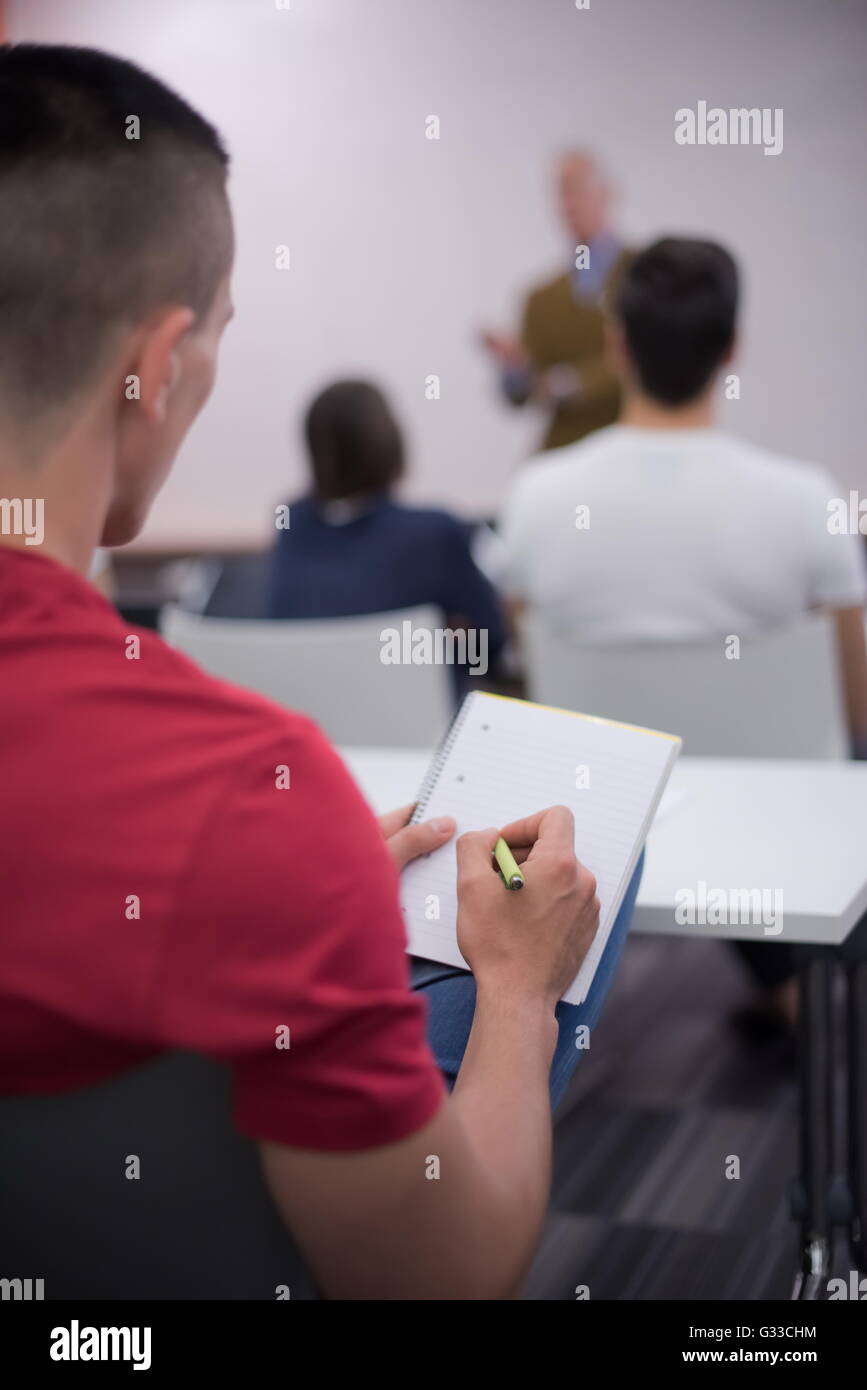 male student taking notes in classroom. business education concept ...