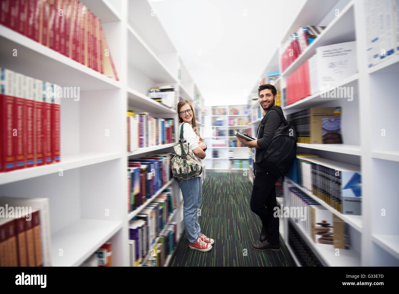 happy students group in school library selecting books to read and ...