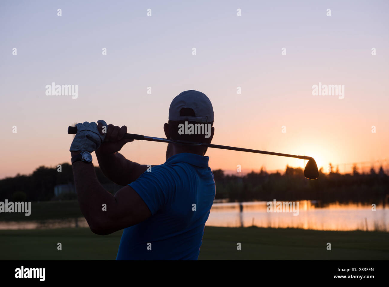 golfer hitting long shot with driver on course at beautiful sunset ...