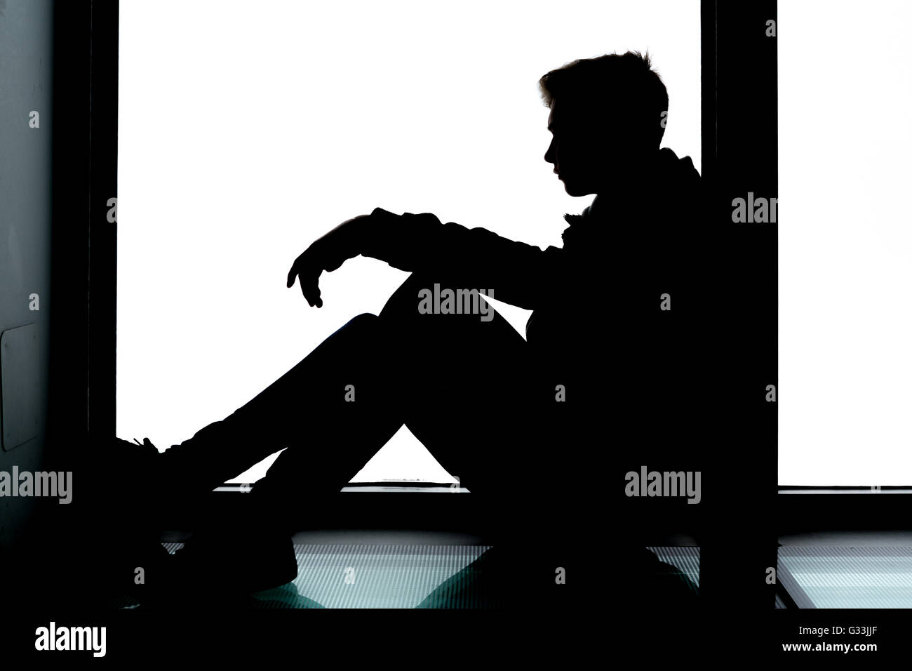 A teenage boy sitting next to a bright window Stock Photo - Alamy