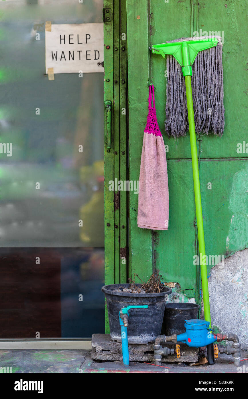 a help wanted sigh on the showcase window of a small shop near a dirty ...