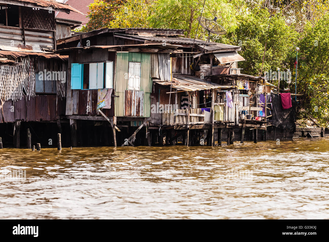 Wooden slums on stilts on the riverside of Chao Praya River in Bangkok ...