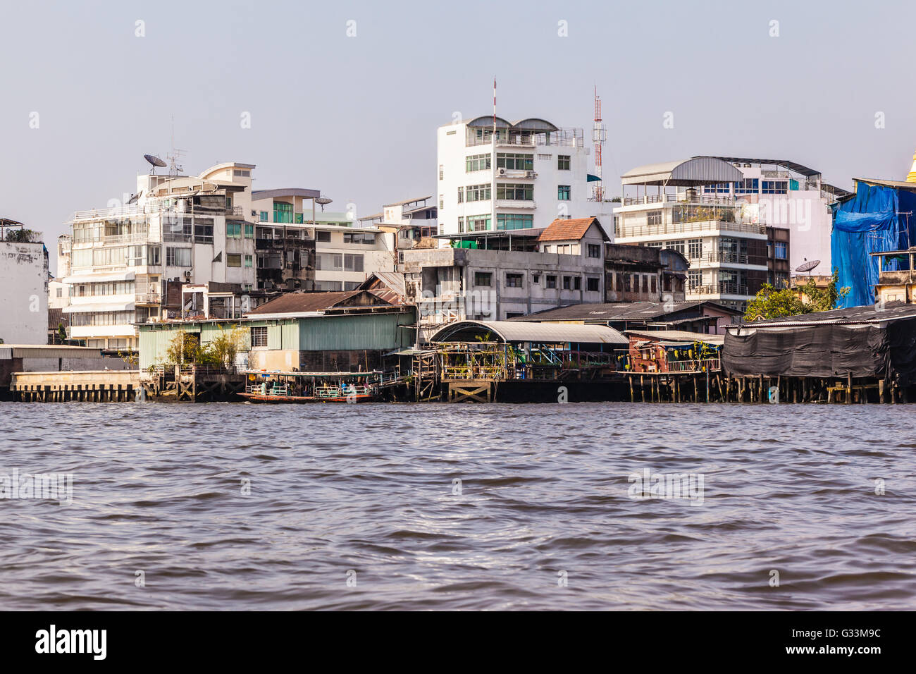 Wooden slums on stilts on the riverside of Chao Praya River in Bangkok ...
