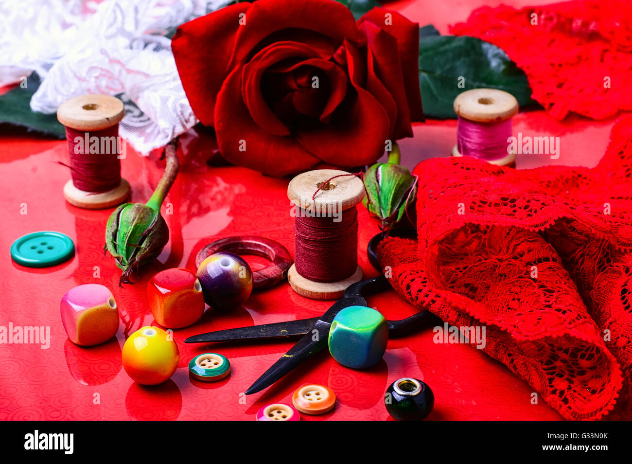 Thread,bead,button, and rose on bright red background Stock Photo - Alamy