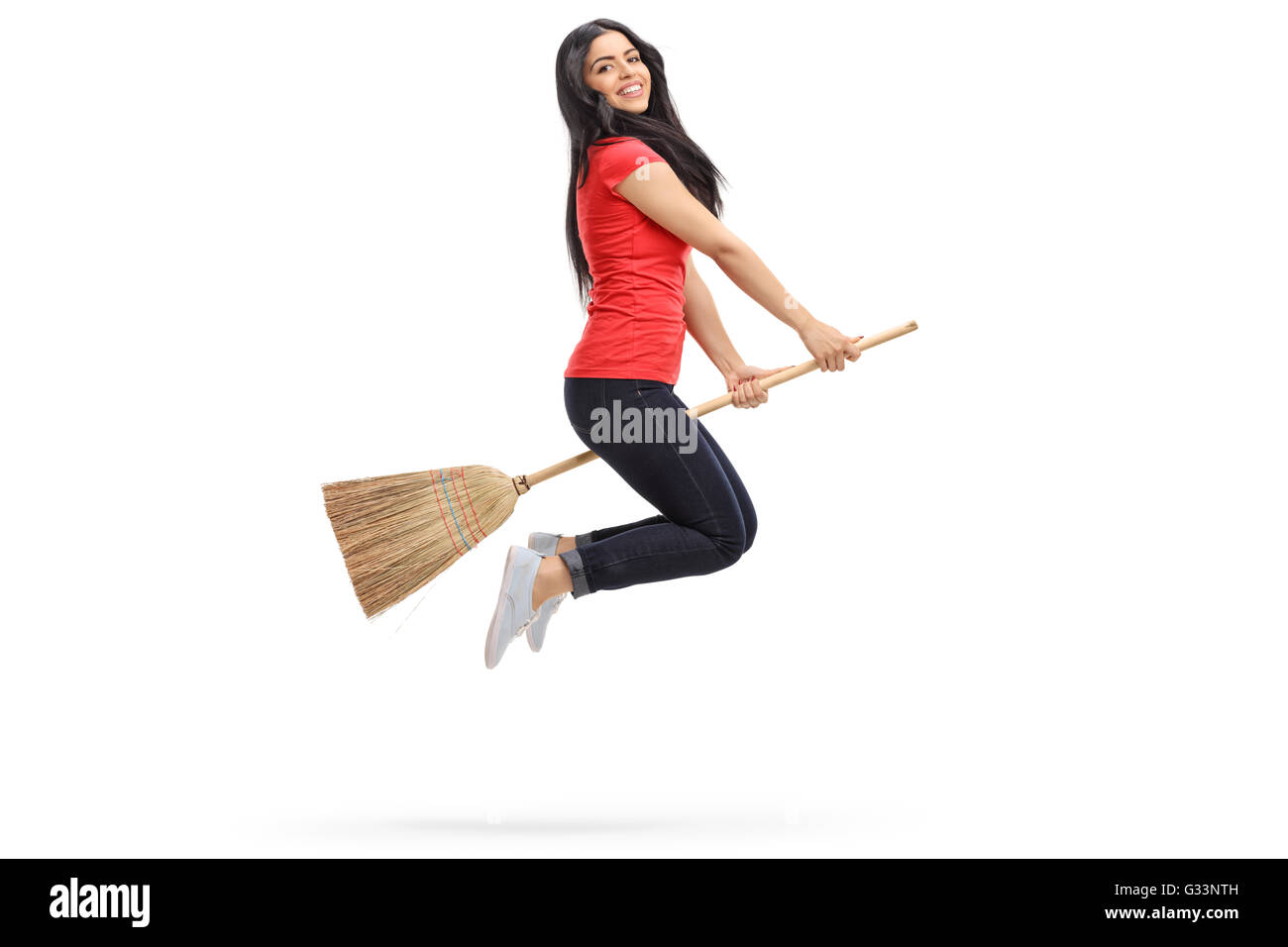 Studio profile shot of a young woman flying on a broom isolated on ...
