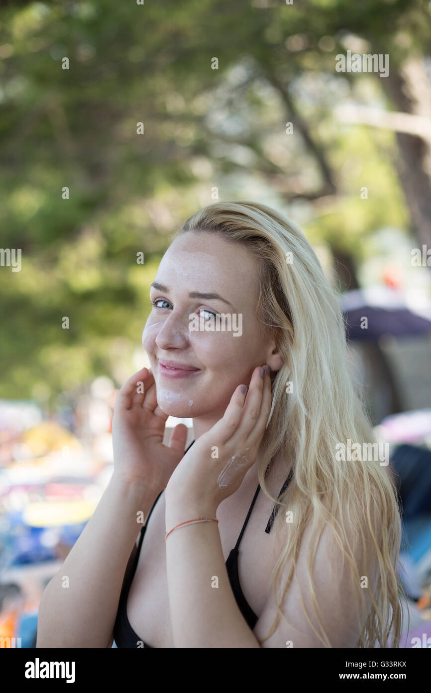 Beautiful blonde woman putting sunscreen on the beach Stock Photo - Alamy