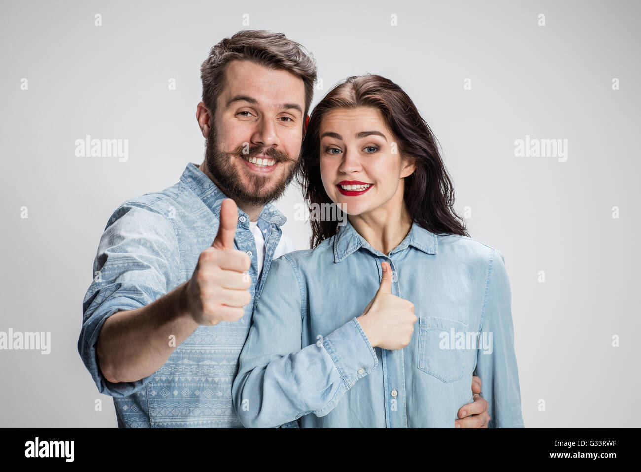 Two young smiling people with thumbs-up gesture Stock Photo - Alamy