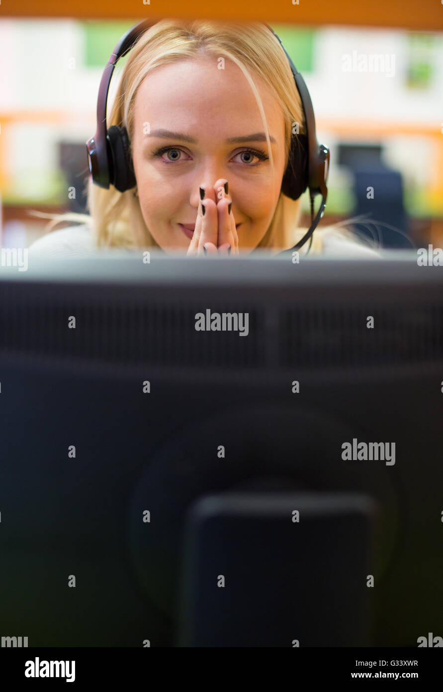 Happy young businesswoman wearing headset while using computer at ...