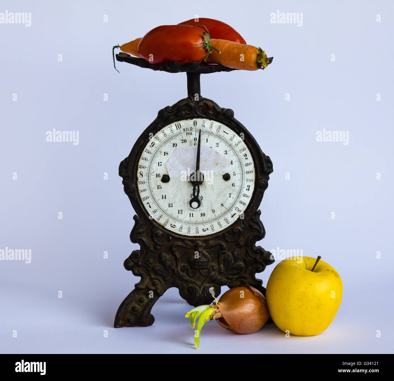 weighing scales with an old cast-iron tomatoes,a carrot,an onion and an ...