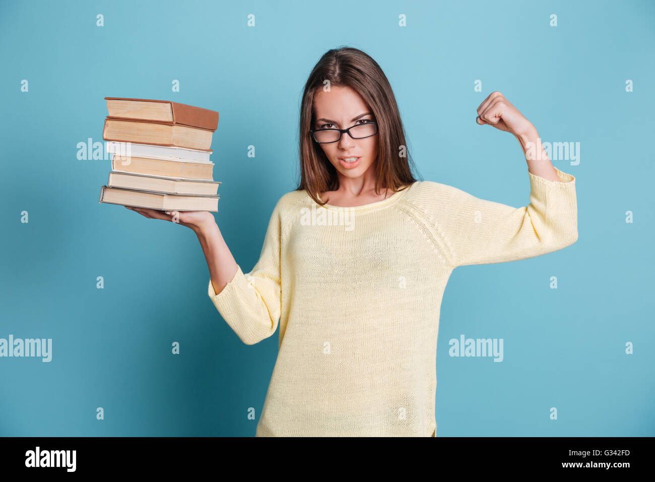 Strong smart girl holding books in one hand wearing eyeglasses isolated ...