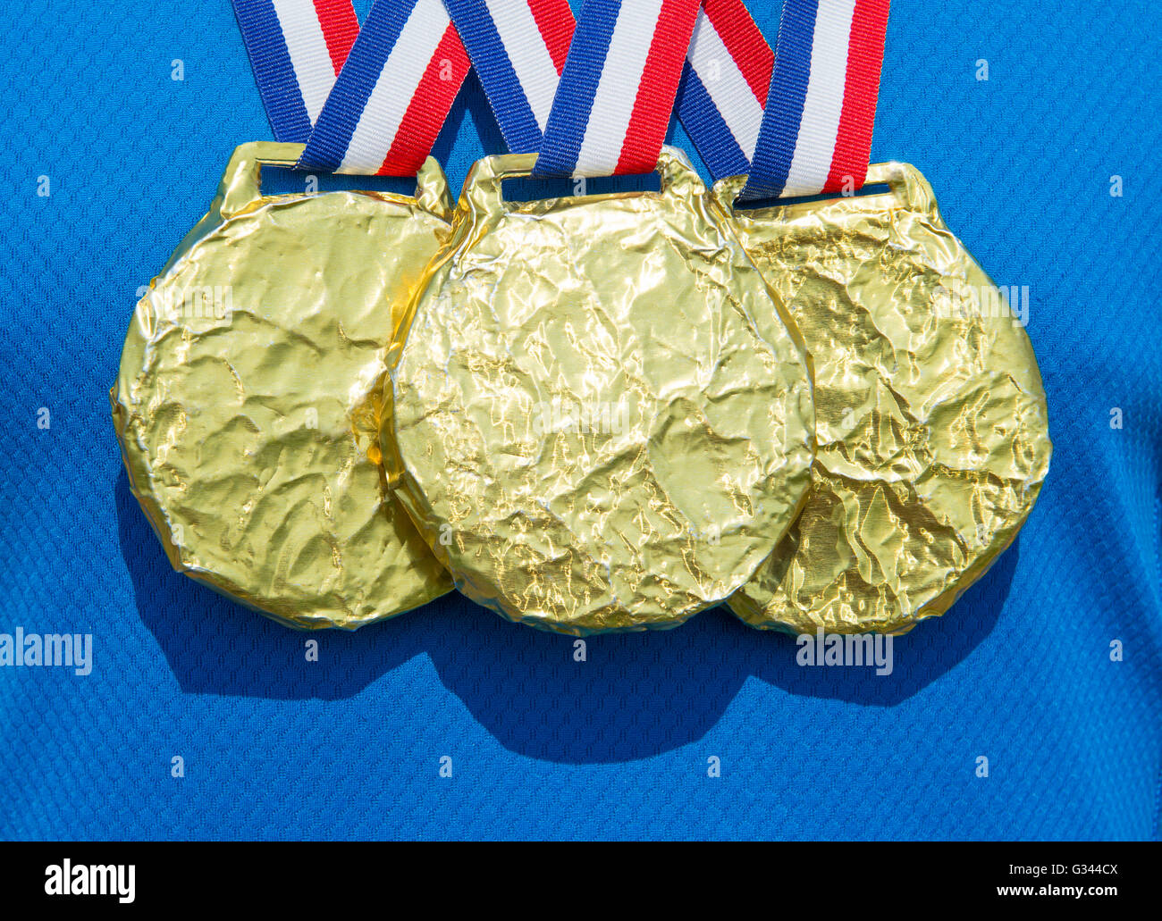 Gold medals hanging from Brazil colors yellow and green ribbon on blue ...