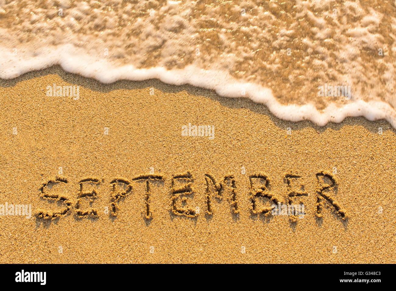 September - written on sandy beach with the soft wave Stock Photo - Alamy