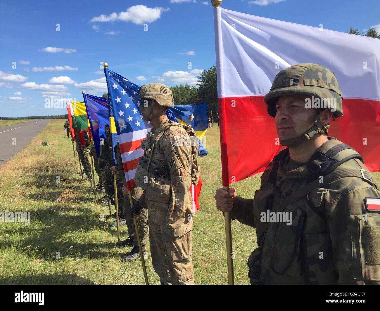 Soldiers representing NATO nationals stand with flags during opening ...