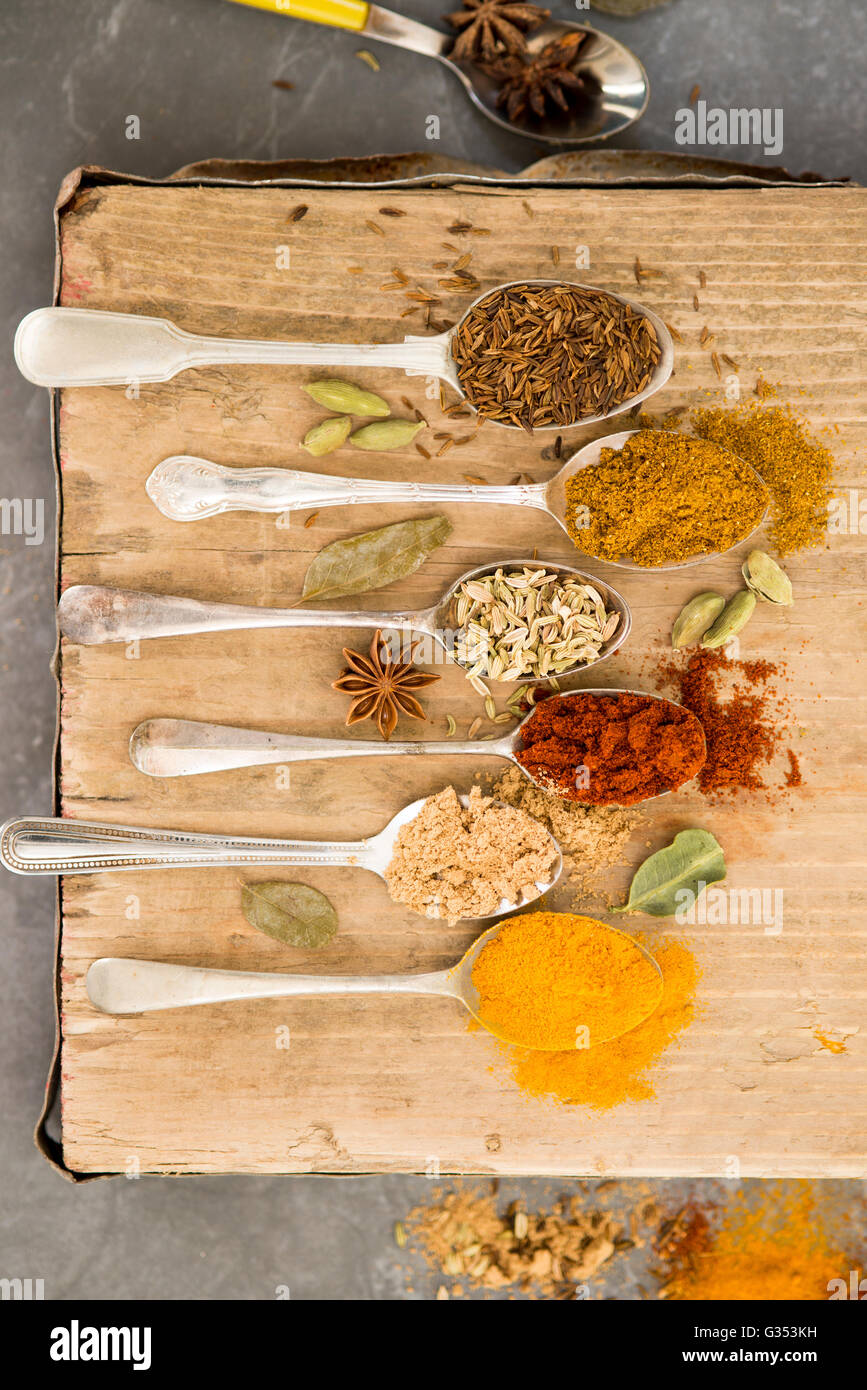 Various spices in silver dining spoons arranged on wooden board Stock ...
