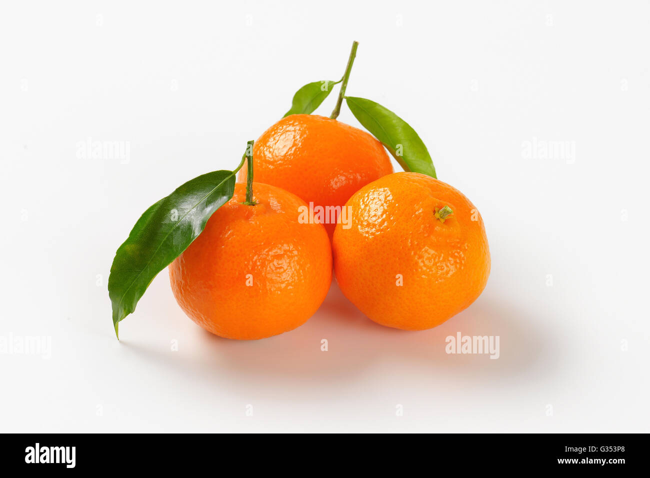 three tangerines with leaves on white background Stock Photo - Alamy