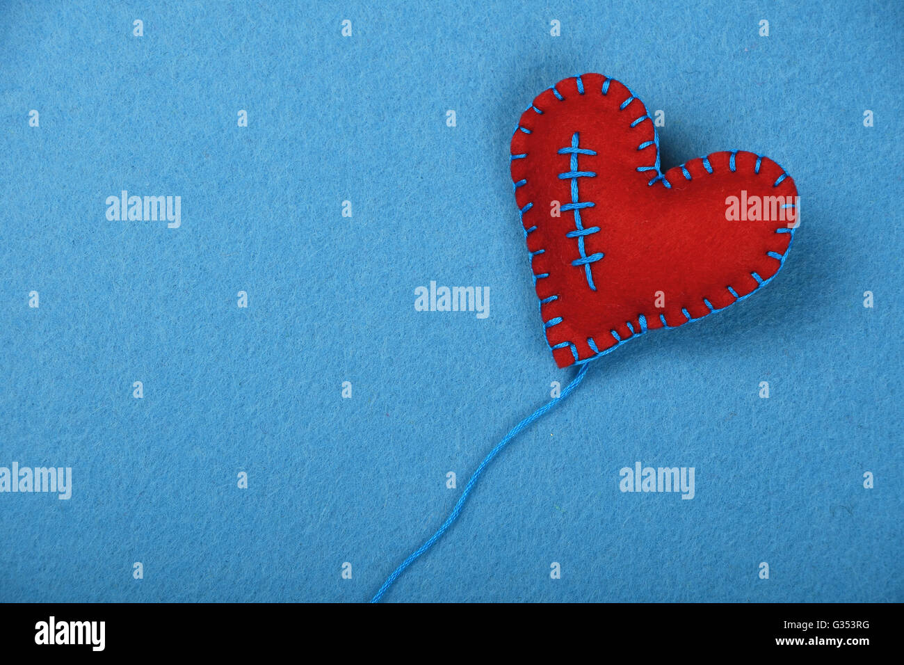 Felt craft and art, one handmade red stitched toy heart with thread on ...