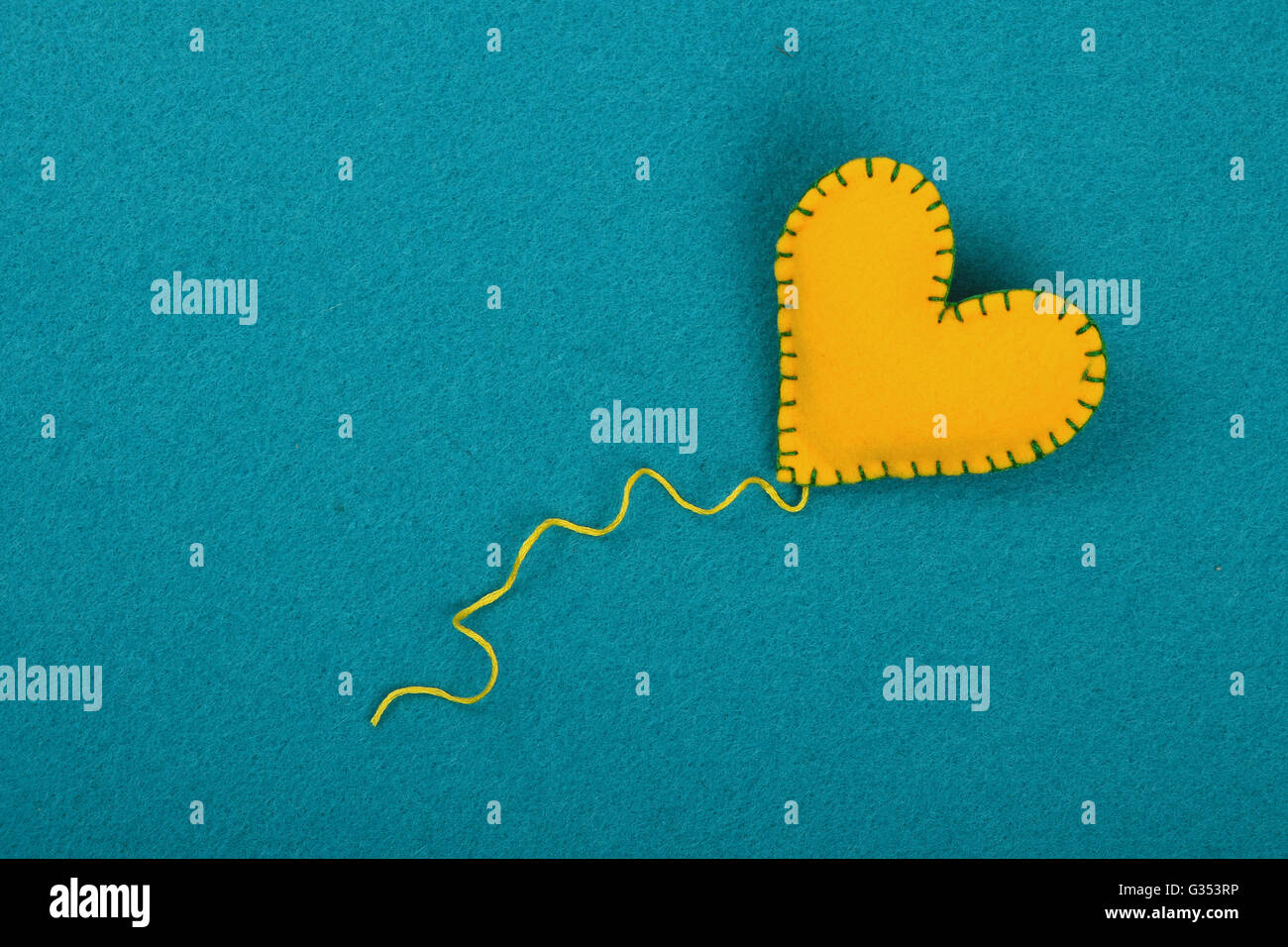 Felt craft and art, one handmade yellow stitched toy heart with thread ...