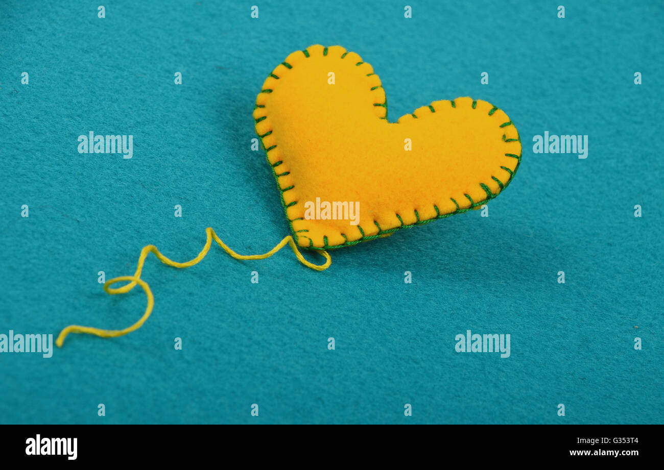 Felt craft and art, one handmade yellow stitched toy heart with thread ...
