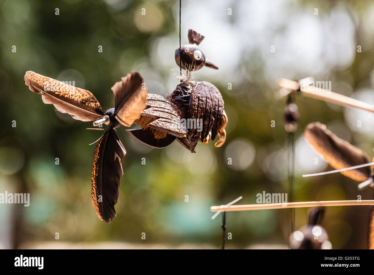 a homemade wooden bird shaped wind toy with feathers hanged with a ...