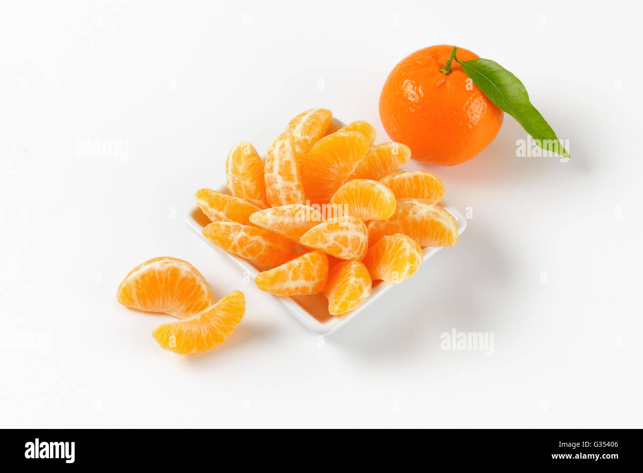 bowl of tangerine segments and whole tangerine on white background ...