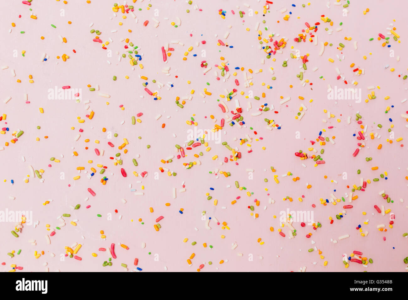 Colorful sprinkles spilled on pink textured background Stock Photo - Alamy