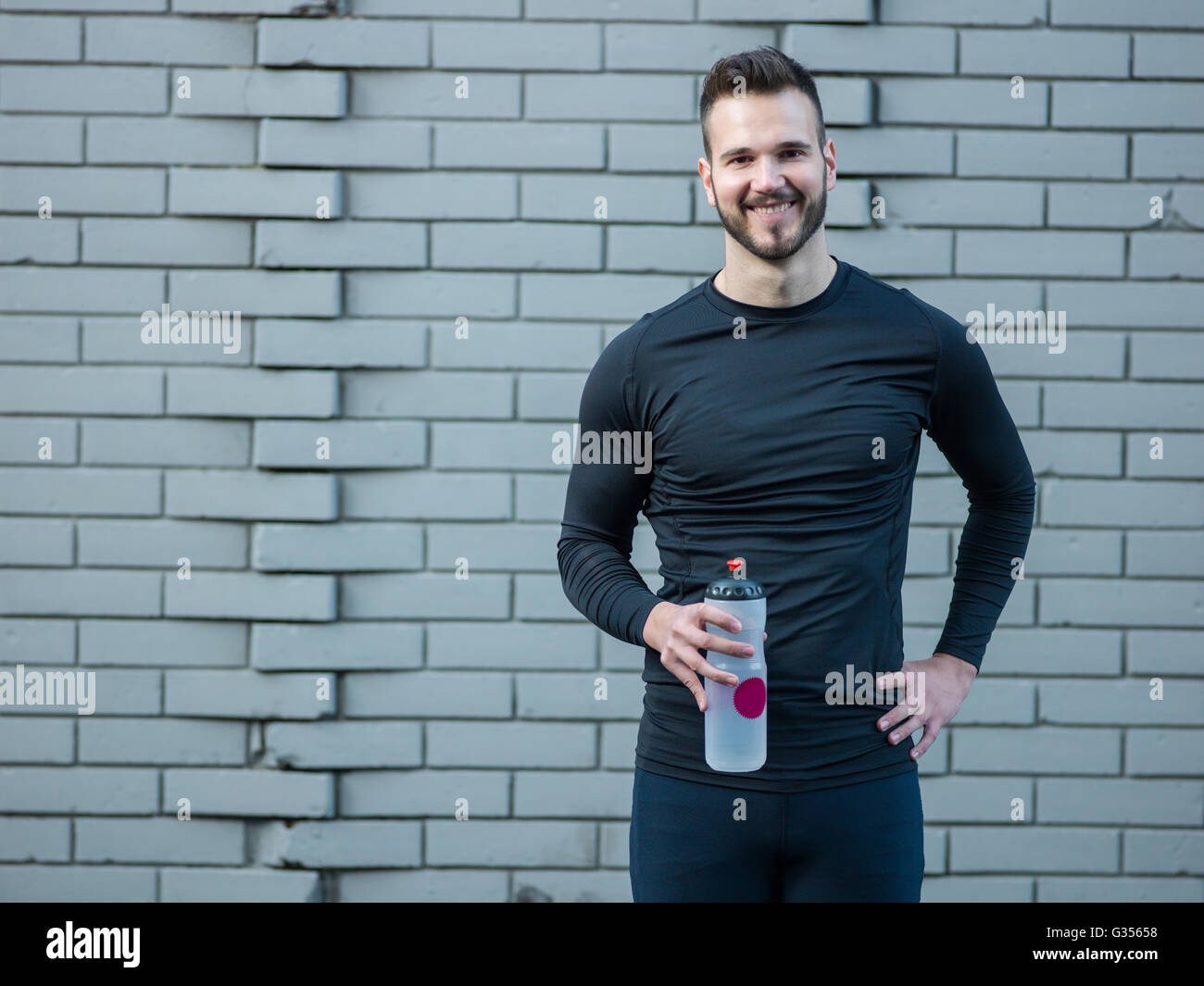 Runner stretching by brick wall Stock Photo - Alamy