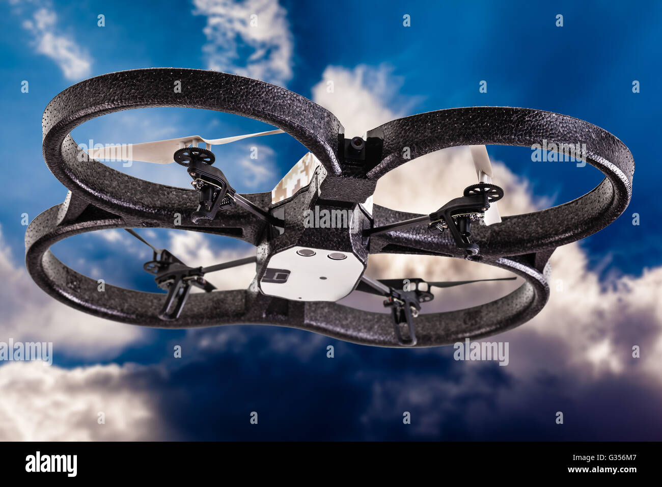 a small spy quad copter drone flying over a dramatic blue sky with ...