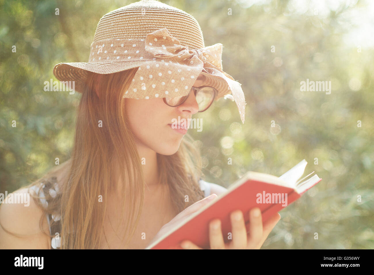 Beautiful country girl reading a book in nature, enjoying sunny day ...