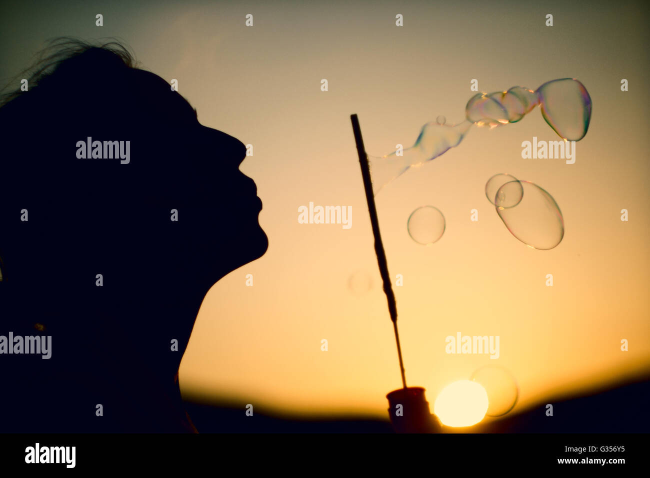 Happy blowing bubbles in the park at sunset. instagram tone, retro tone ...