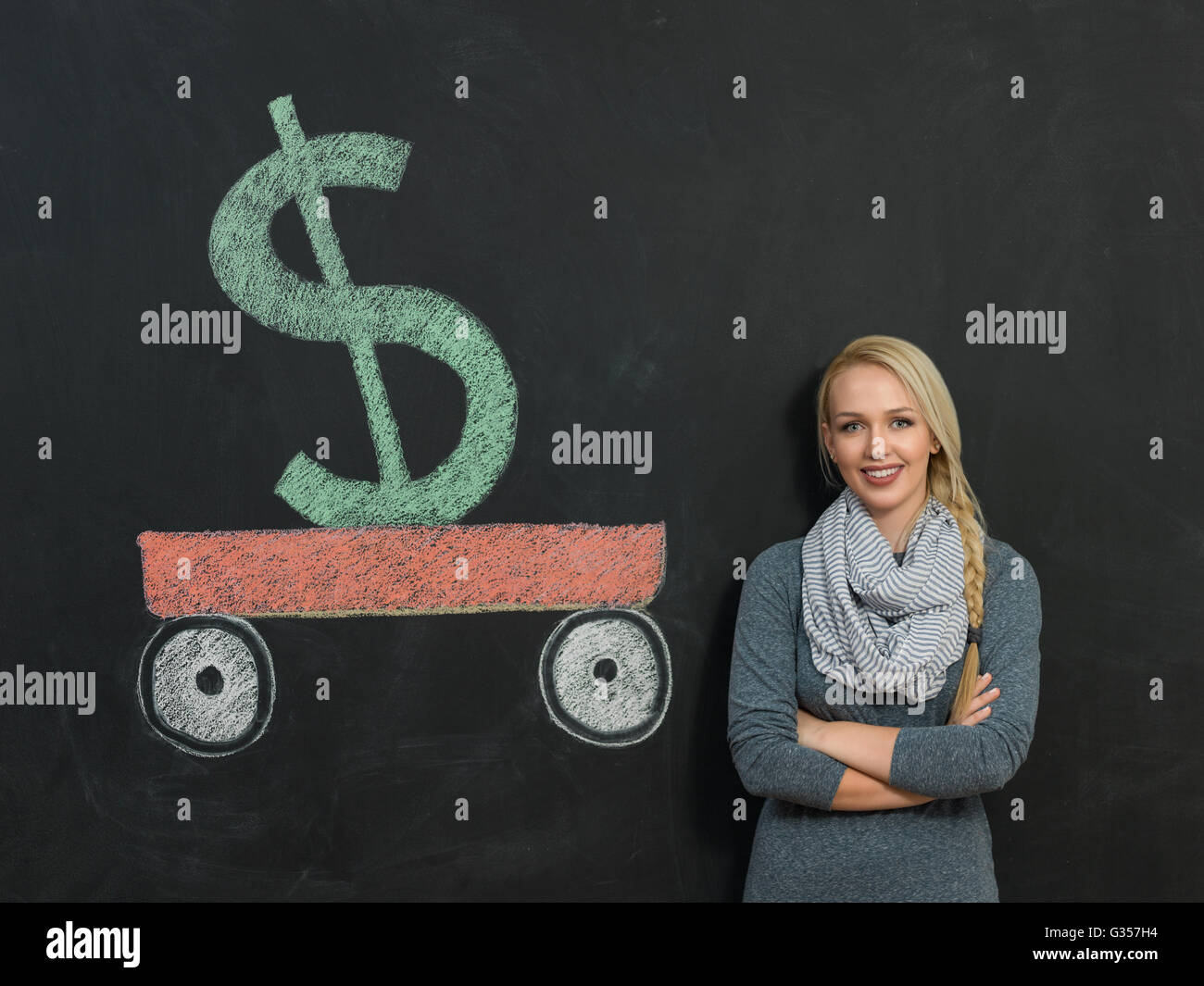 Happy woman standing in front of dollar sign written on a chalkboard ...
