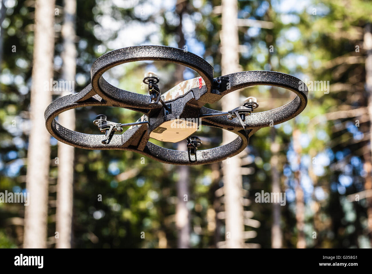 a small spy quad copter scout drone flying through the trees in a ...