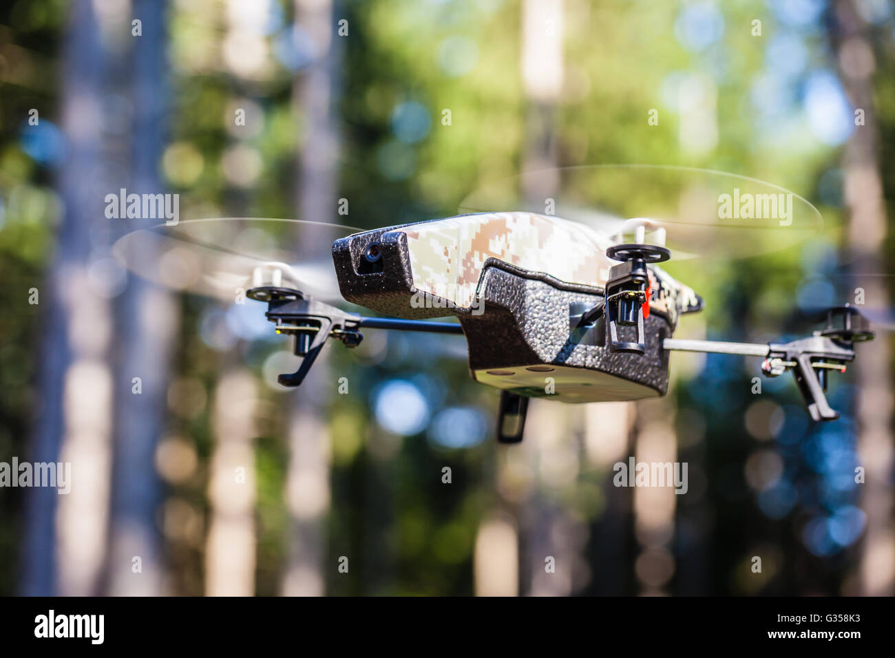 a small spy quad copter scout drone flying through the trees in a ...