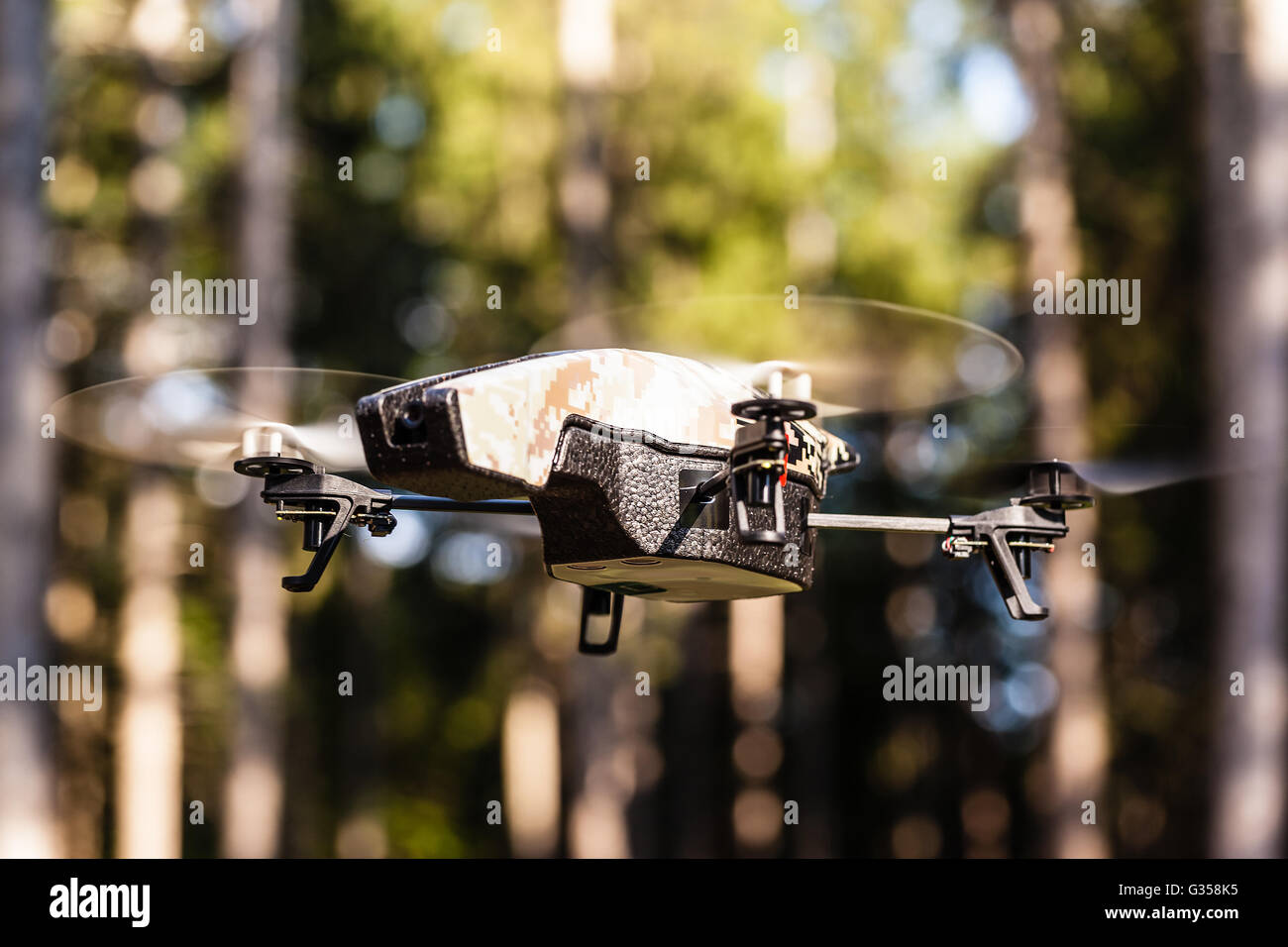 a small spy quad copter scout drone flying through the trees in a ...