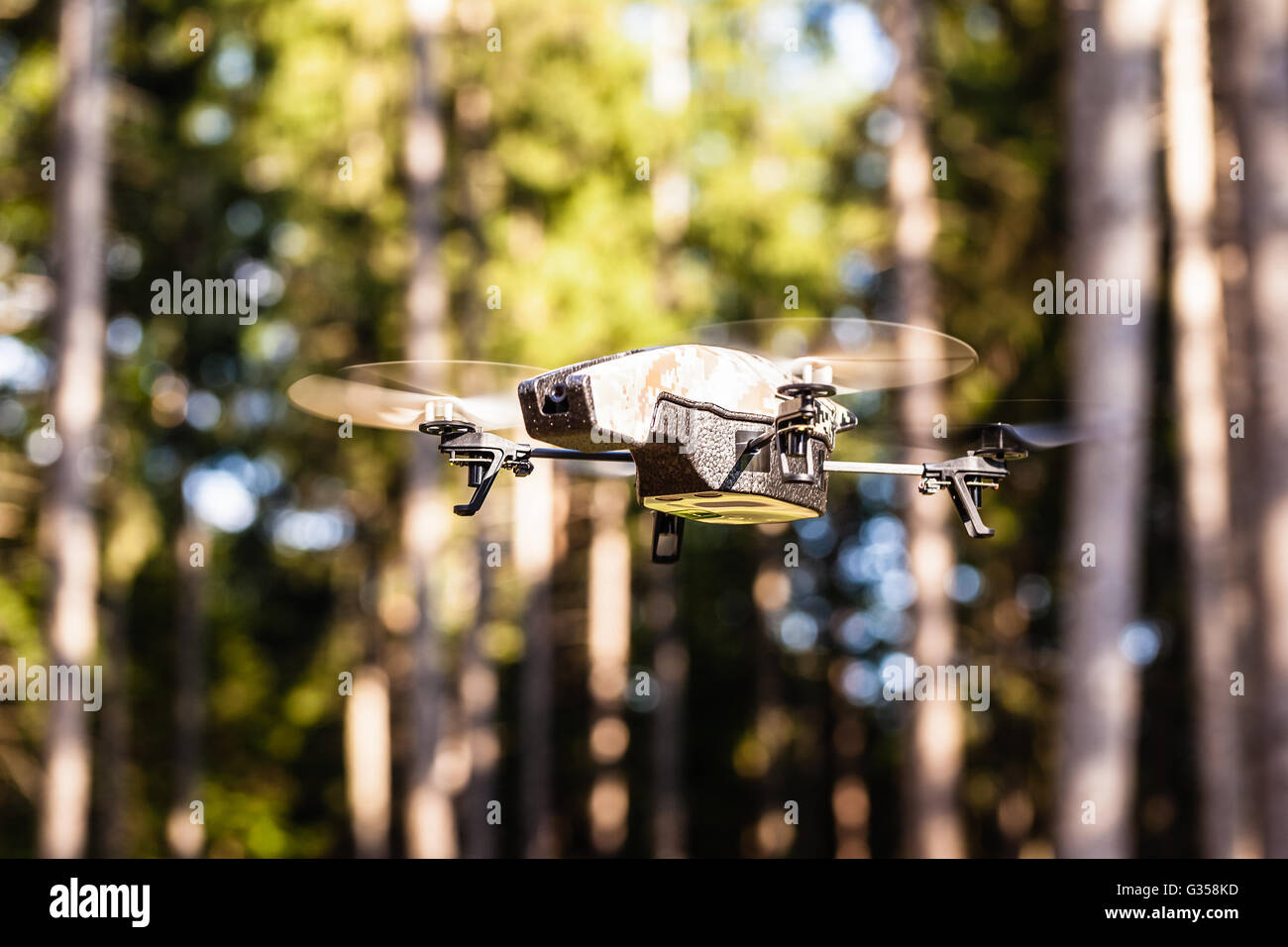a small spy quad copter scout drone flying through the trees in a ...
