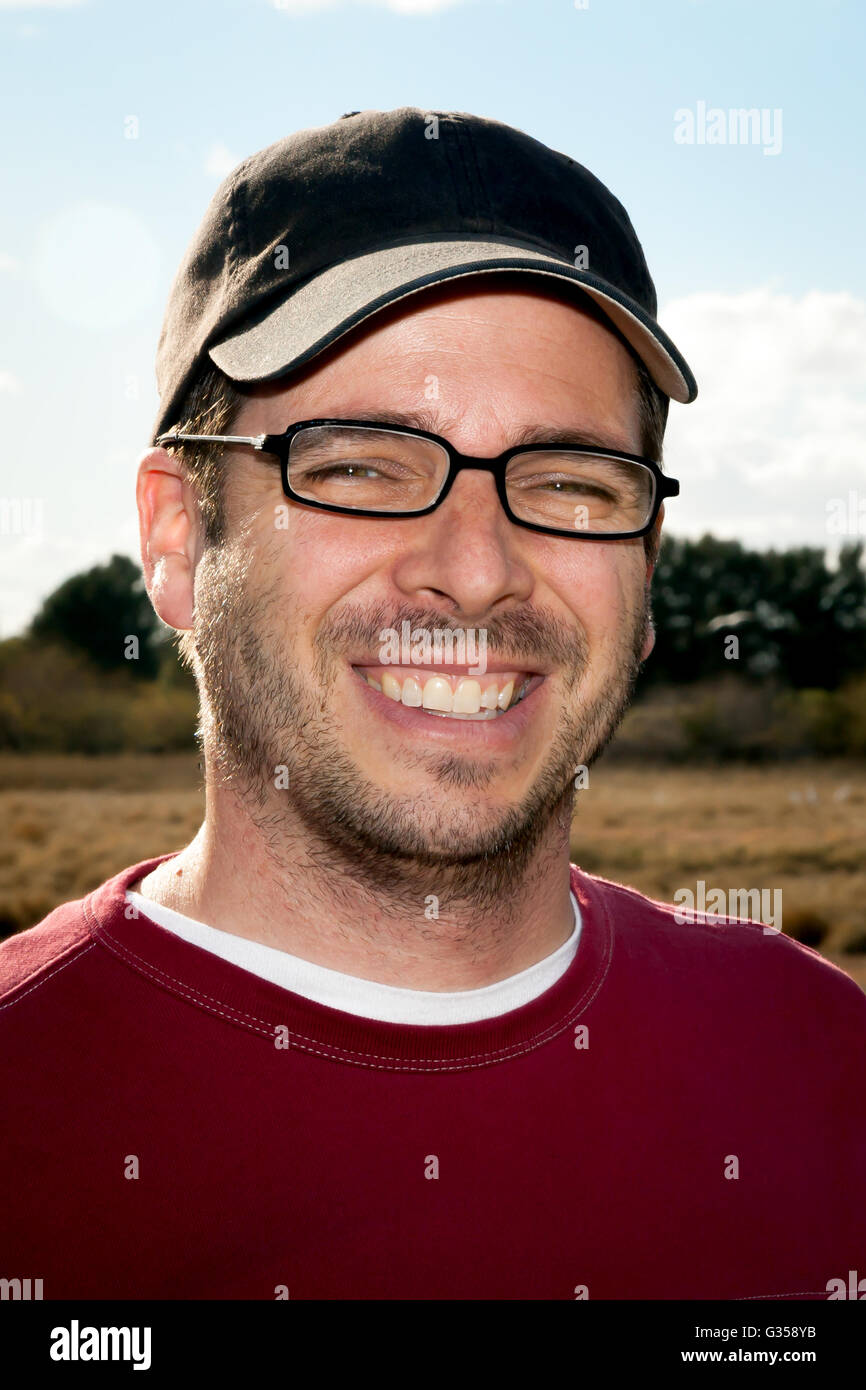 Handsome man looking a bit goofy with facial stubble, reading glasses ...
