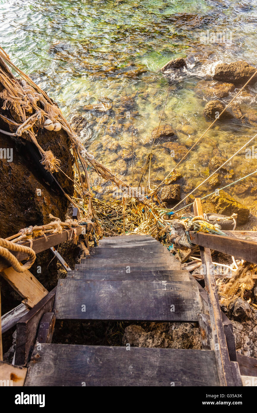 an old and unsafe wooden staircase leading to the ocean with a lot of ...